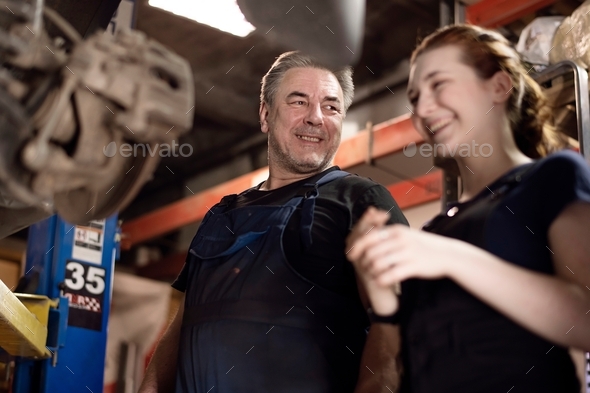 ↟ Professional car mechanic and his young student work in an automobile ...