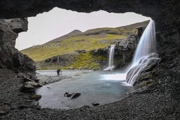 Natural rock cave frames a beautiful nature landscape and waterfalls ...