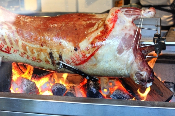 Roasting a pig on a spit over hot coals Stock Photo by iheartcreative