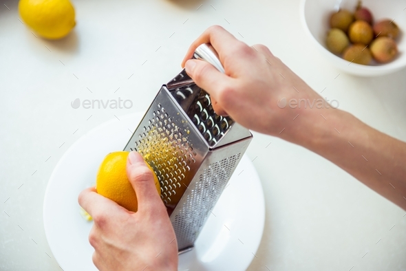 Top view male hands grating fresh whole lemon on metal hand grater ...