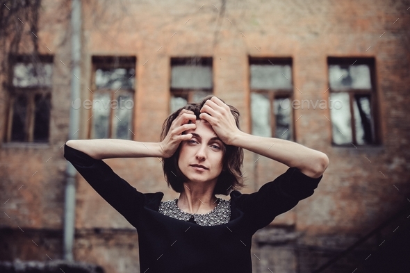 portrait of emotional and stressed woman on dark retro building ...