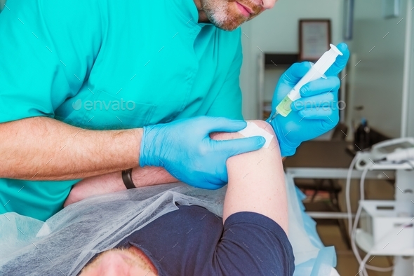 Neurologist doctor makes an injection therapy (blockade) into elbow ...