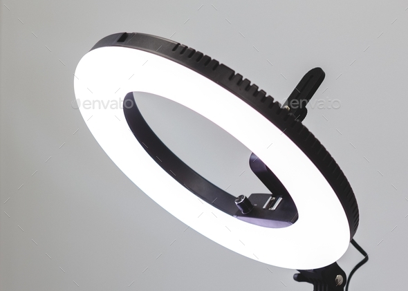 White lit up ring light for portrait photography in front of a plain ...
