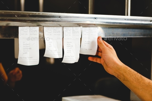 Restaurant worker grabbing lists and receipts of orders for food Stock ...