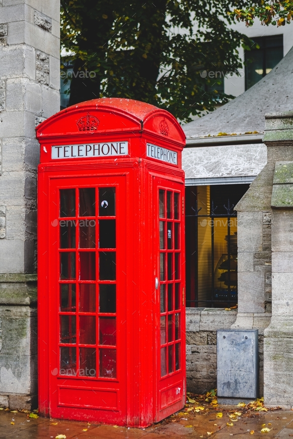 Bright red telephone box phone booth in England among neutral grey ...