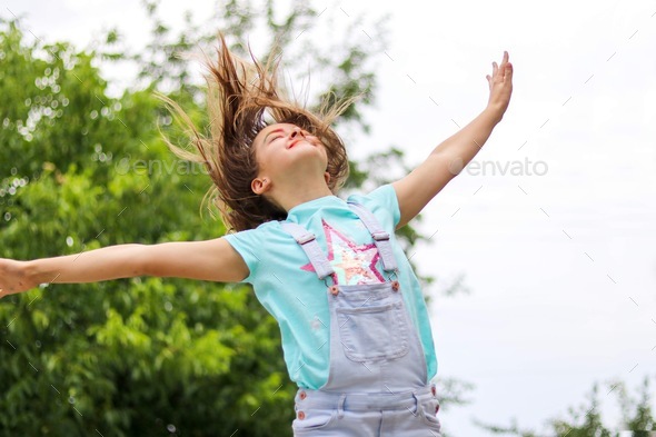 Preteen happy girl gimping in the air with her hands up. Summer ...