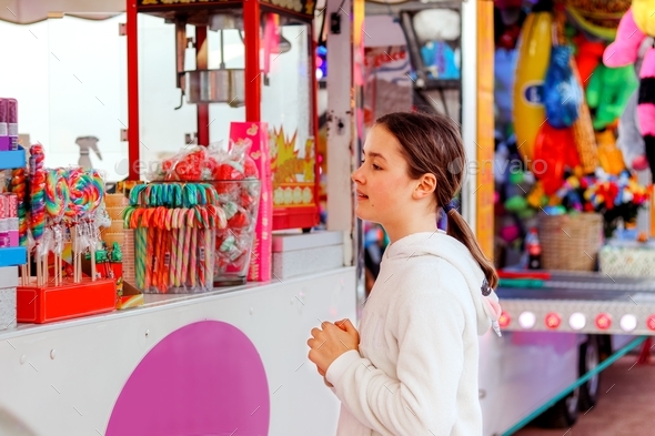 Cute tween girl looking with desire at bright colorful sugar candies ...