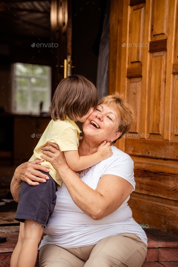Happy grandmother hugging her little grandson who is kissing her ...
