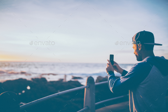 Young man snapping photo of beach with smart phone Stock Photo by ...