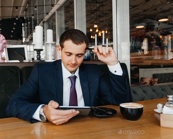 Handsome young businessman smiles and drinks coffee in a cafe. man in a ...