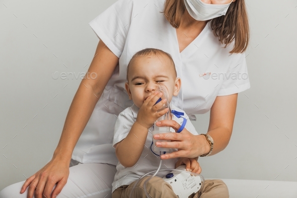 The doctor makes an inhalation procedure for a little boy. high quality ...