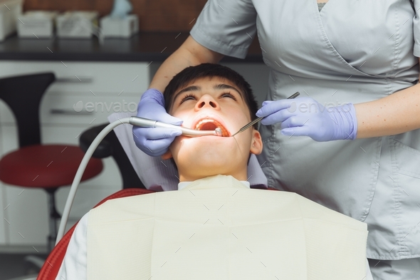 Drilling teeth and sucking saliva with an ejector. dentist treats ...