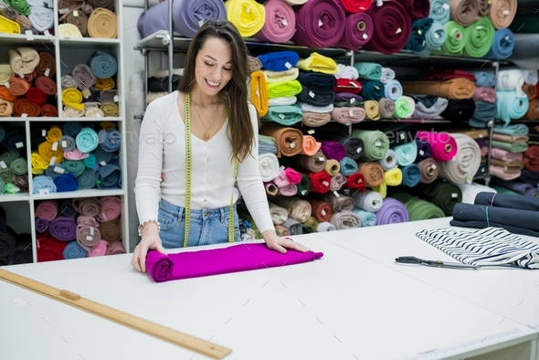 Woman seller standing near work place in fabric store. Owner textile ...