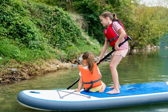 Happy two girls learning stand up paddleboards. Stock Photo by ...