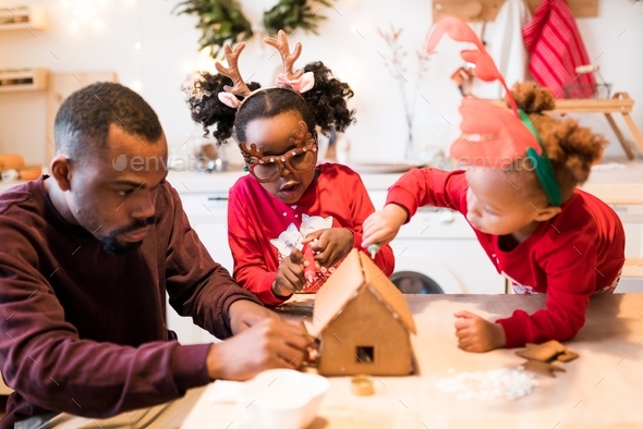 African american father and daughters decorating gingerbread house ...
