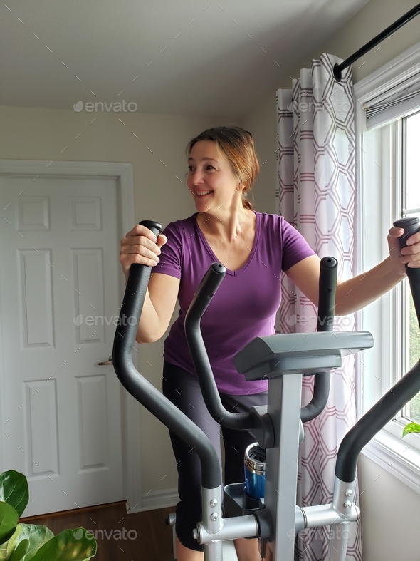 Older woman doing exercises on elliptical trainer for healthy body ...