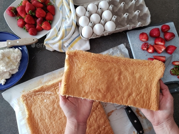 Overhead view of cake making step cutting bisquit sheet cake to create ...