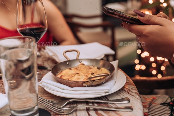 Using mobile while having dinner at a restaurant Stock Photo by Elisall