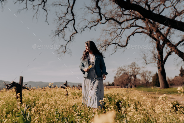 Woman staring into the distance in a flower field Stock Photo by Elisall