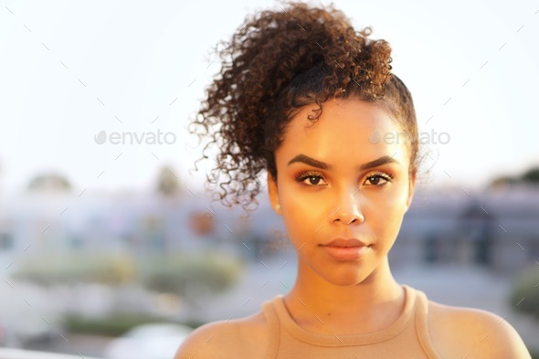 Beautiful bold and serious woman with curly hair looking into camera ...