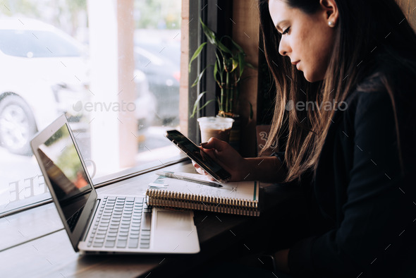 Professional woman using laptop computer and mobile phone while working ...