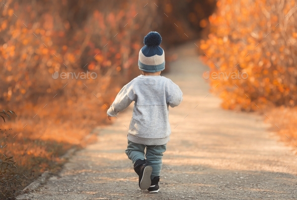 Little boy running on the road past autumn leaves Stock Photo by ...