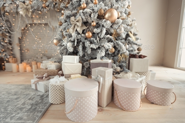 Christmas presents under a luxury decorated snow-covered tree in pastel ...