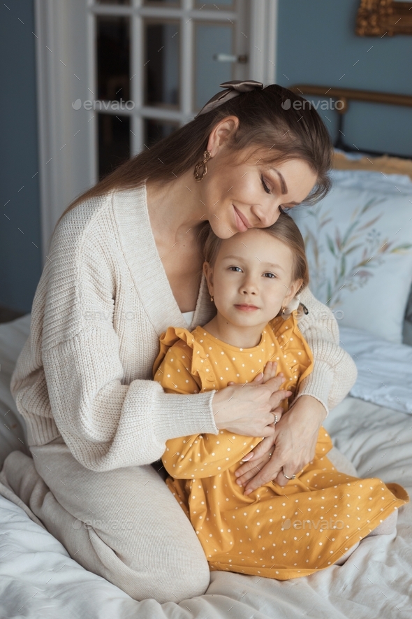 Loving beautiful young mother hugging her little daughter at home on bedroom in cozy bed Stock ...
