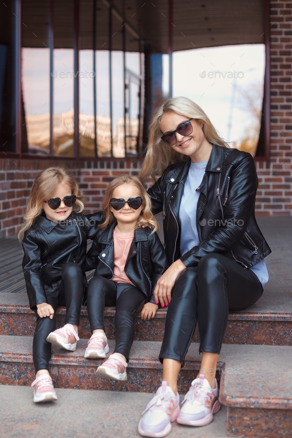 Urban family portrait of young stylish mother and two little daughters ...
