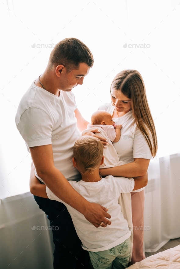 Family with two children hug each other with newborn baby. Candid ...