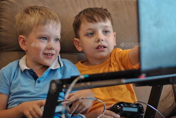 Two little boys kids playing computer games sitting together on the ...