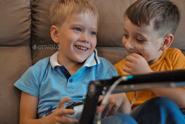 Two happy little boys kids playing together in computer games and ...