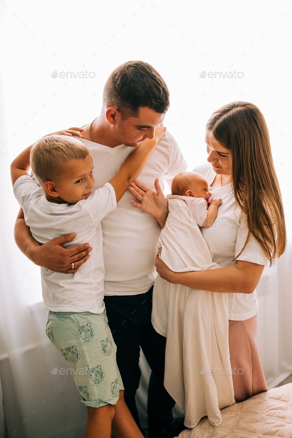 Family with two children hug each other with newborn baby. Candid ...