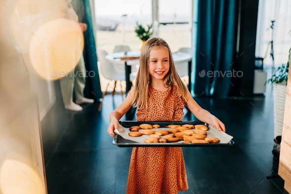 Kid girl child cooked cookies and bringing them to the table on the ...