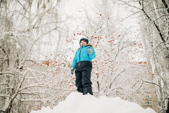 Little kid boy outdoors on the snow wearing winter clothes. Children ...