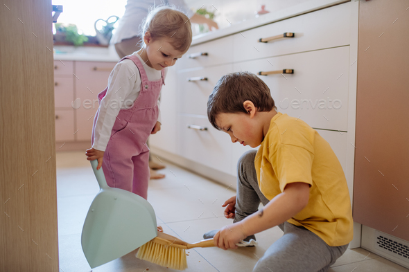 Little boy and girl helping to clean house using pan and brush as they ...