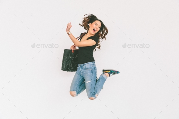 A happy woman jumping in the air against a plain white background ...