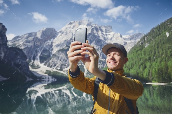 Smiling young man (tourist) taking selfie against Lake Braies and ...