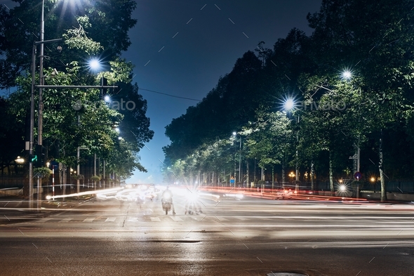 Motorcycles waiting on crossroad. Light trails of traffic in city ...