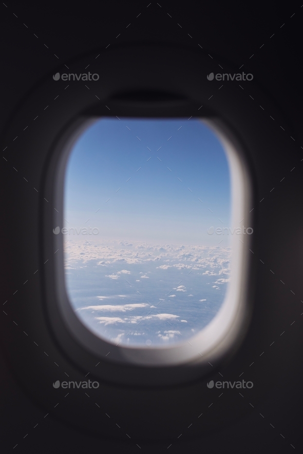 Window of airplane during flight above clouds on beautiful sunny day. Stock Photo by Chalabala
