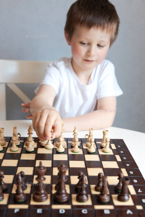 A cute Caucasian boy of 6 years old makes a chess piece move Stock ...