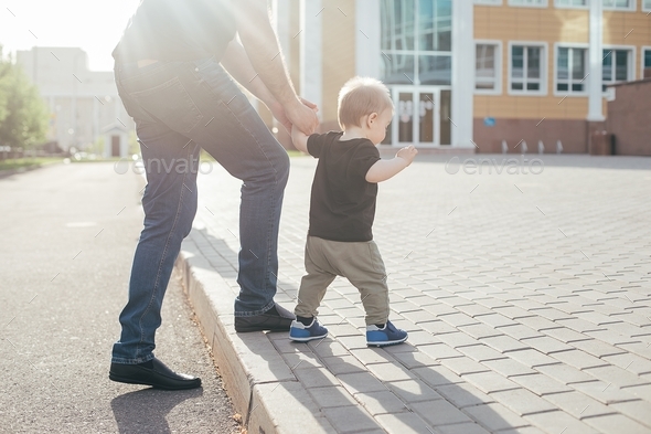 Father and Son walking together. Baby taking first steps with father ...