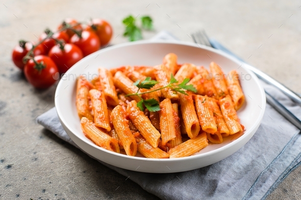 Penne pasta with tomato sause in white plate on stone background table ...
