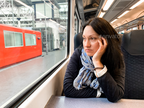 Young woman is traveling in a train. Looking through the window ...