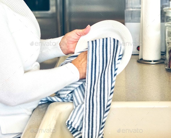 Adult female drying a plate by a kitchen sink Stock Photo by ChantelleL3
