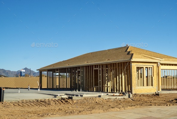 A framed house under construction and a concrete slab foundation with ...