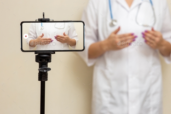 Female doctor blogger recording video on a smartphone standing o Stock ...