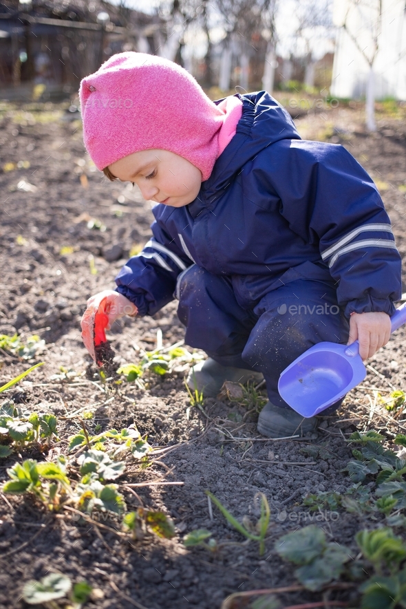 Happy little girl playing and digging in the garden Stock Photo by ...