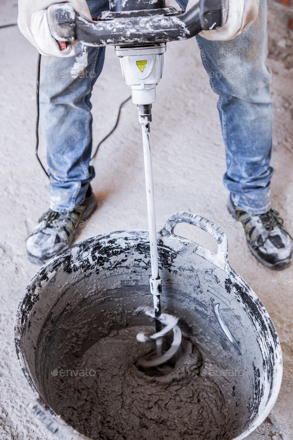 A mason prepares the cement in a bucket with the help of a mixer. Stock ...