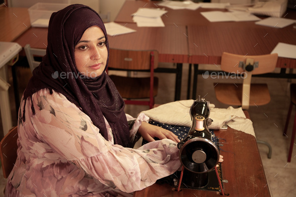 A seamstress of Arab origin sews a garment on her sewing machine. Stock ...